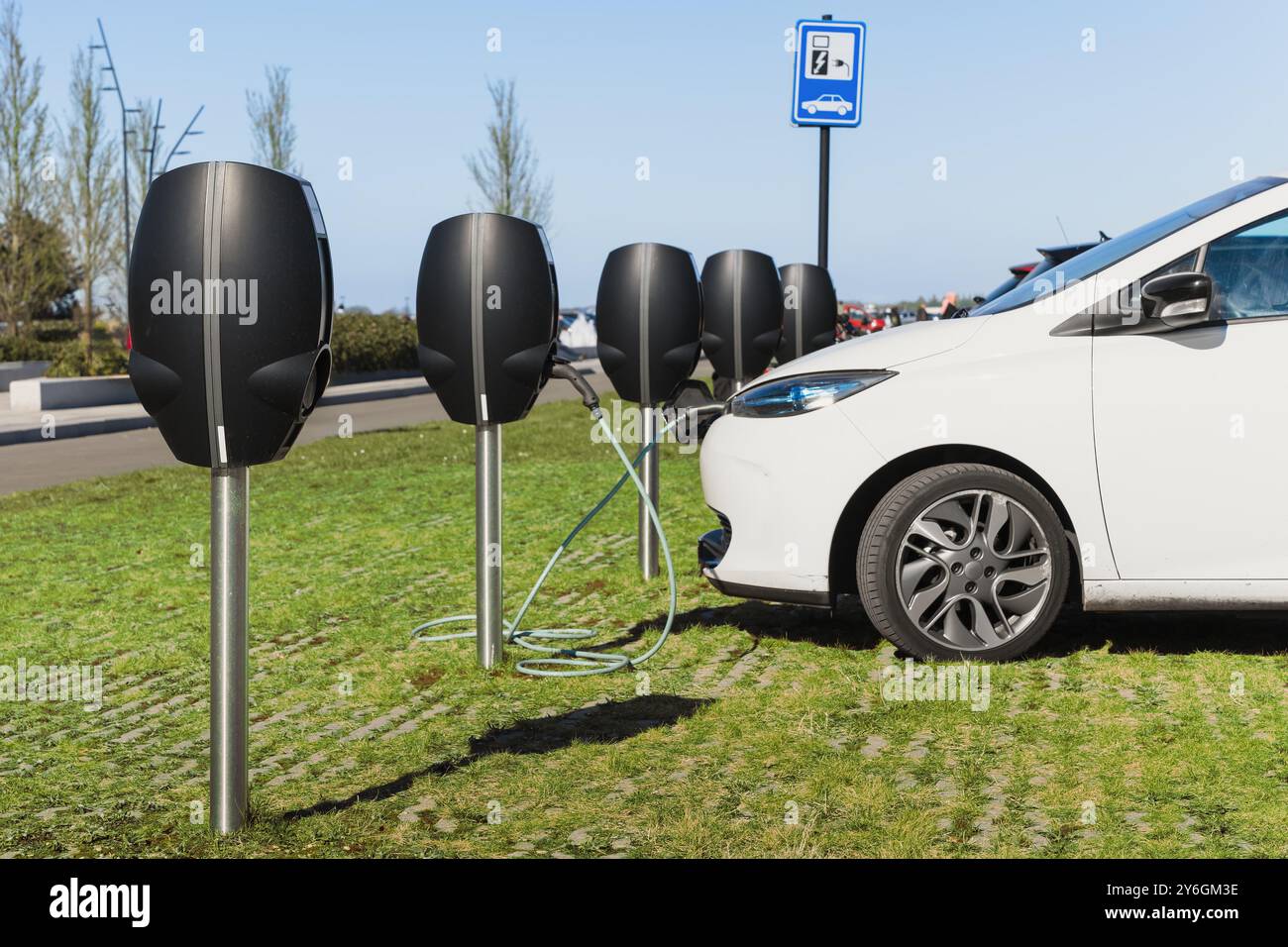 An electric car is connected to a fast-charging station outdoors, eco ...