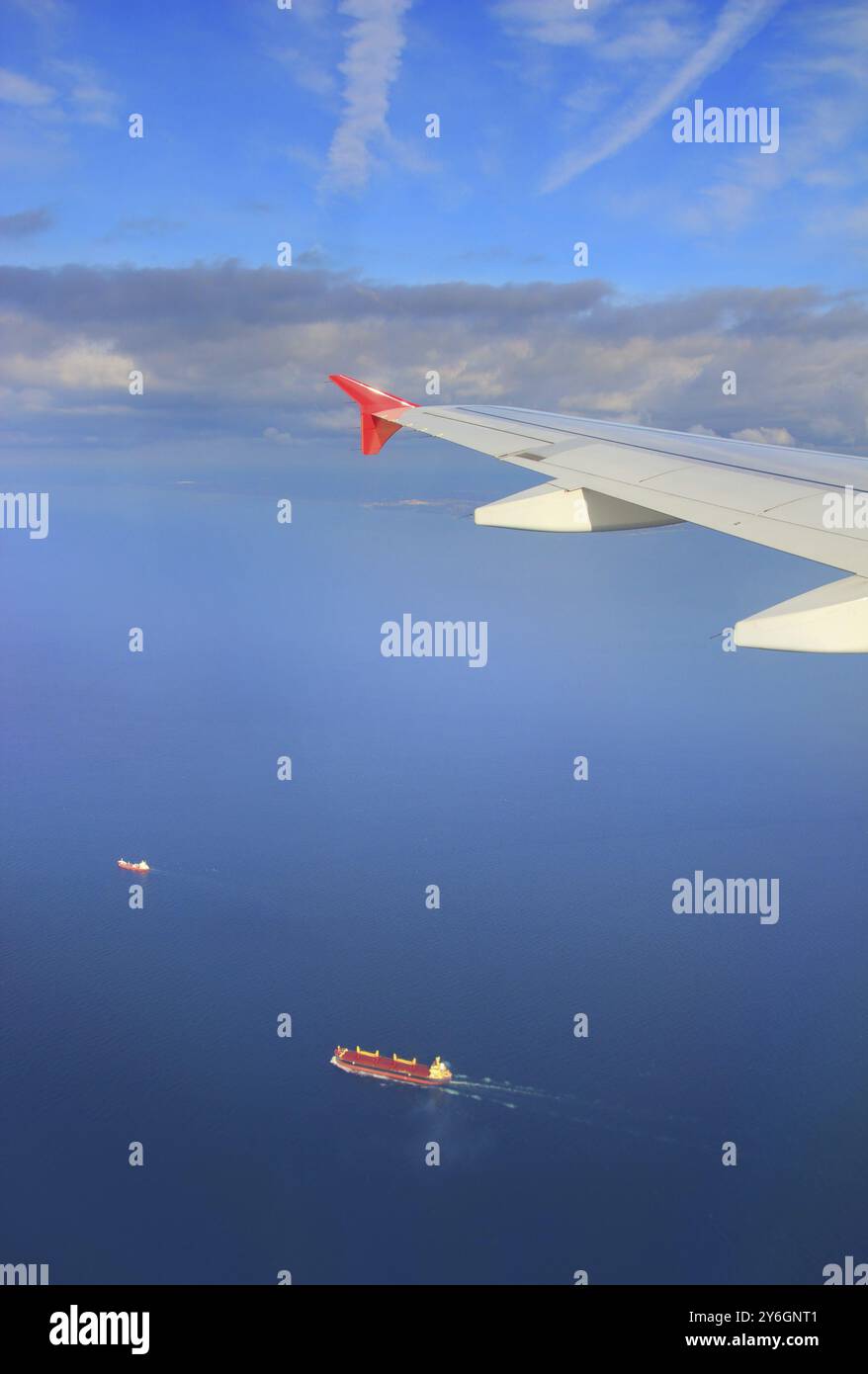 Transportation, cargo ships under wing of flying plane Stock Photo - Alamy