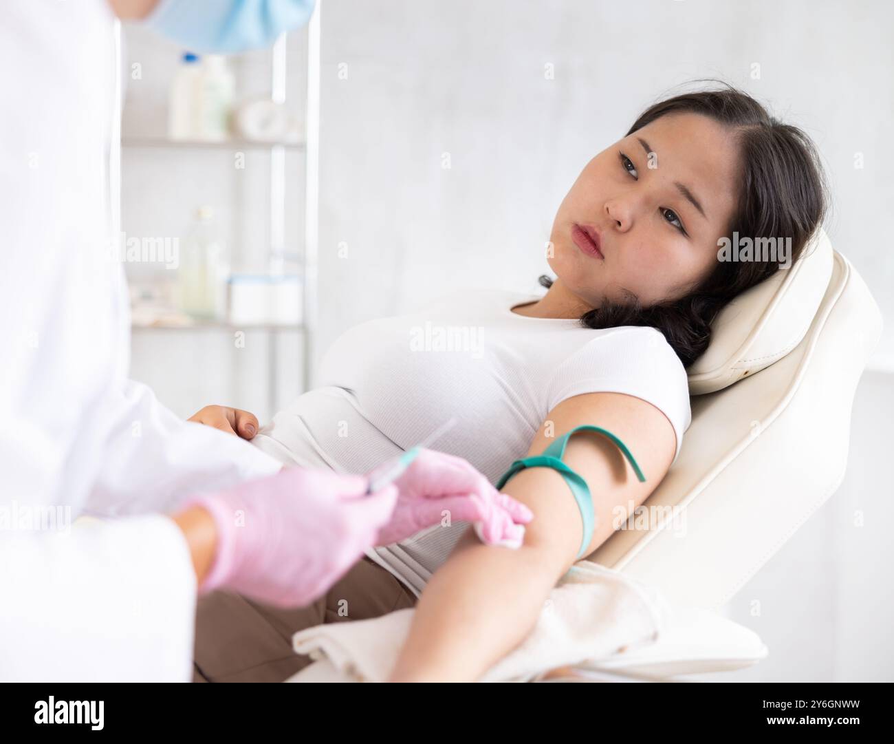 Female anesthesiologist injecting anesthetic into a vein on her arm ...