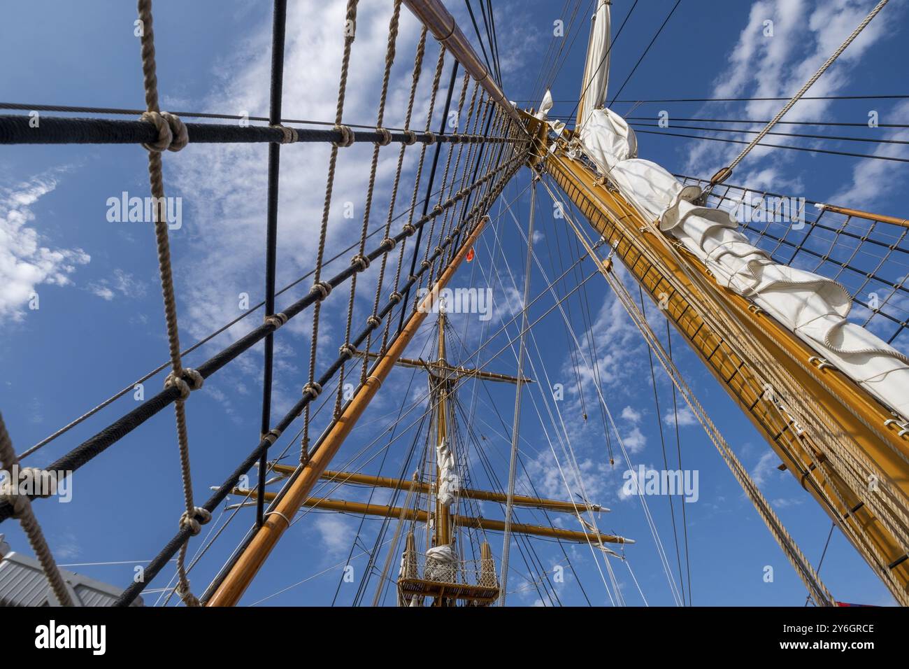 Low angle view of sailboat wooden ship masts and rigging under blue sky ...