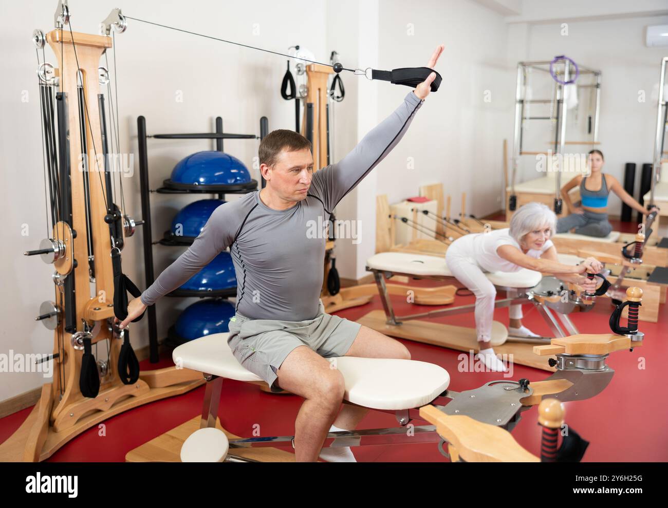 Sports club man client on reformer with cable and rope performs ...