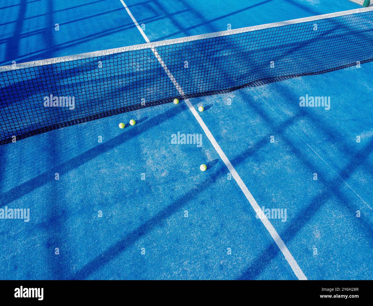 five balls near the net in a padel tennis blue turf court , aerial view ...
