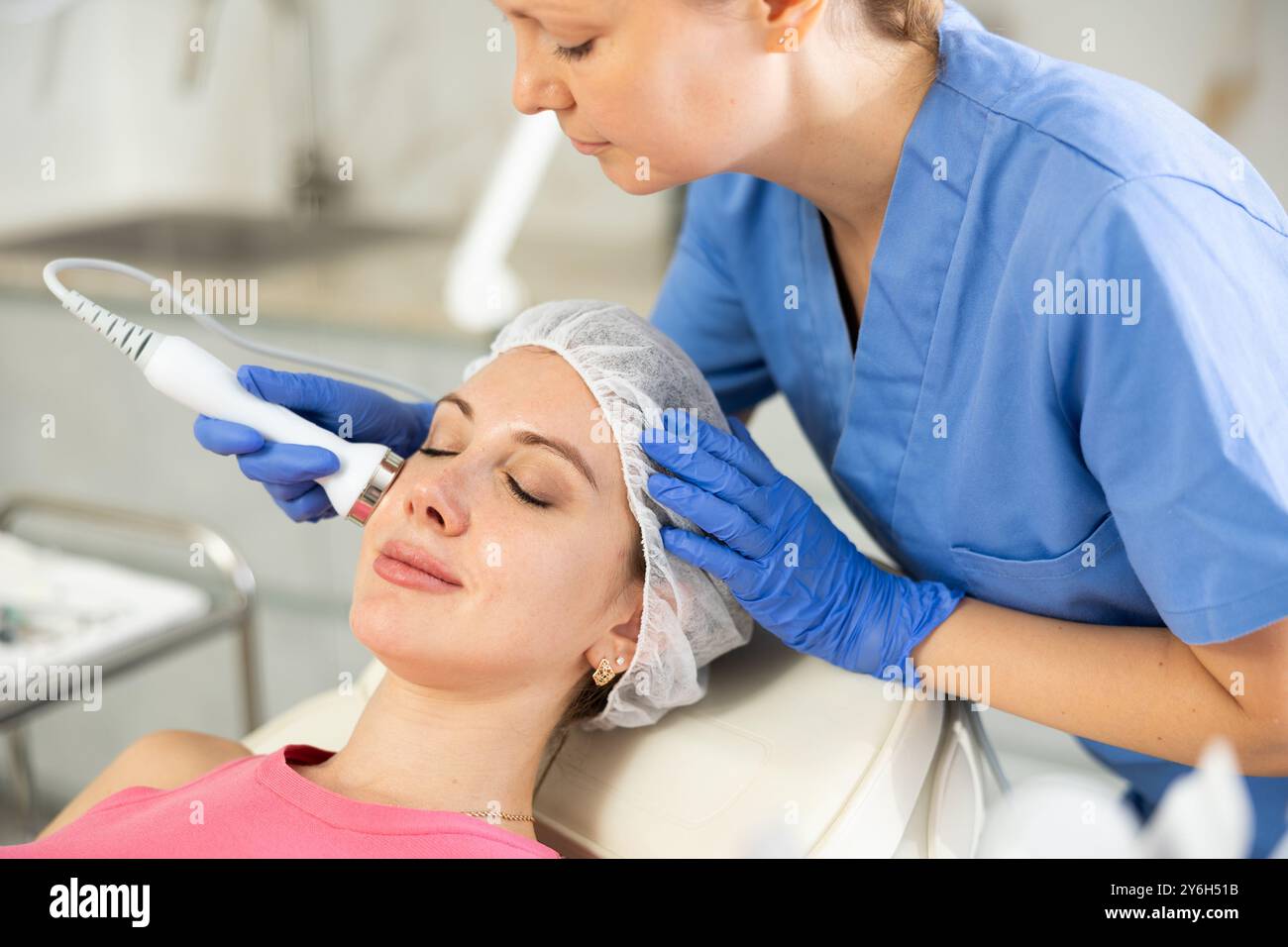 Young girl visitor receiving hardware electric massage and moisturizing ...