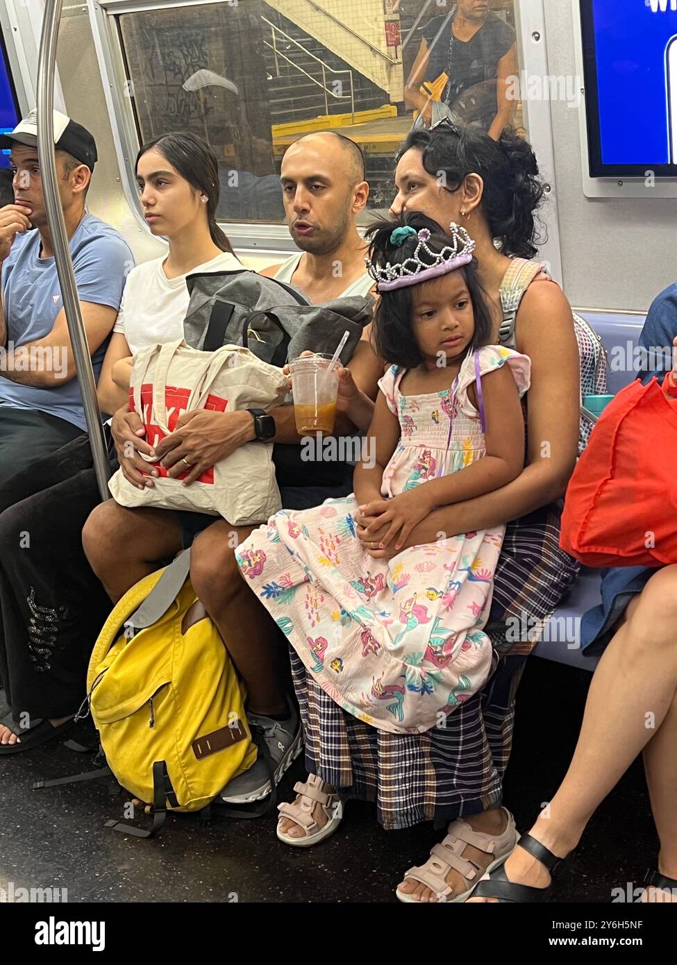 Child with a crown rides a New York City subway train with her parents ...