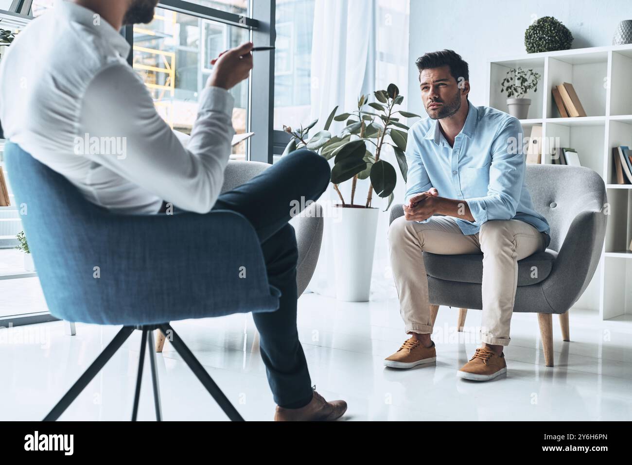 Sharing his problems. Young frustrated man solving his mental problems while having therapy ...