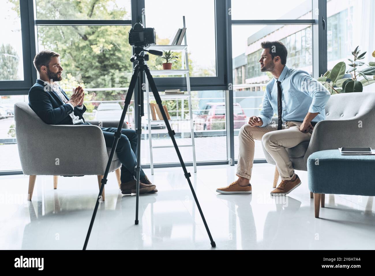 Filming interview. Two young men in smart casual wear talking while ...
