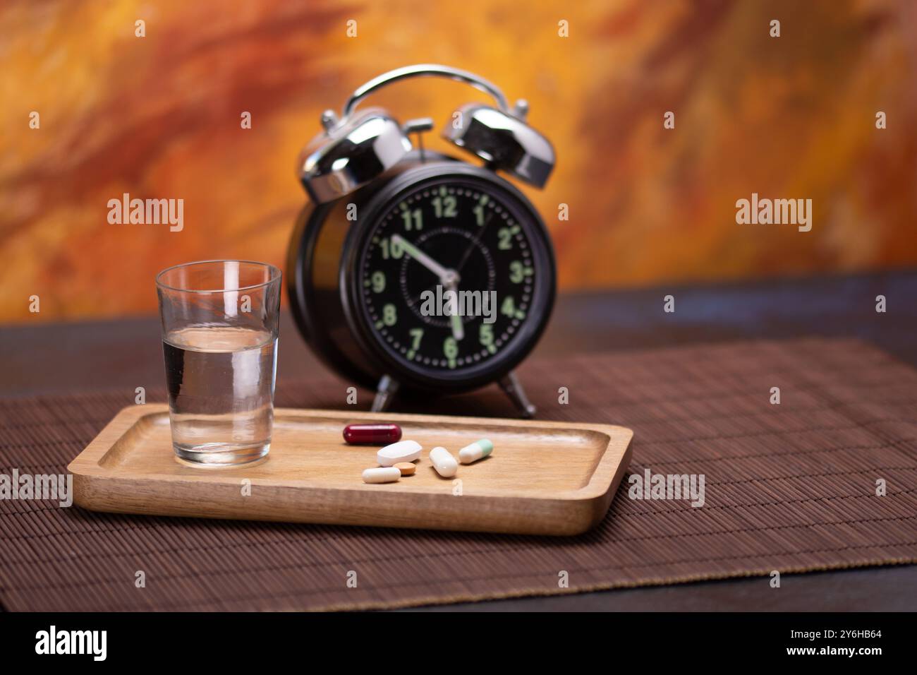 Medication and water on wooden tray with alarm clock background Stock ...