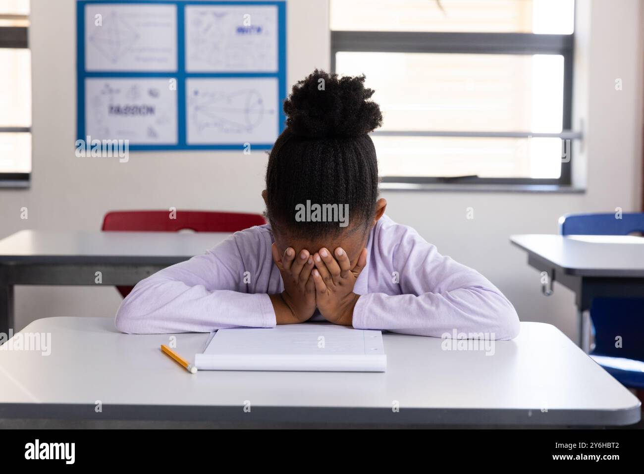 In school, african american girl covering face with hands while sitting ...