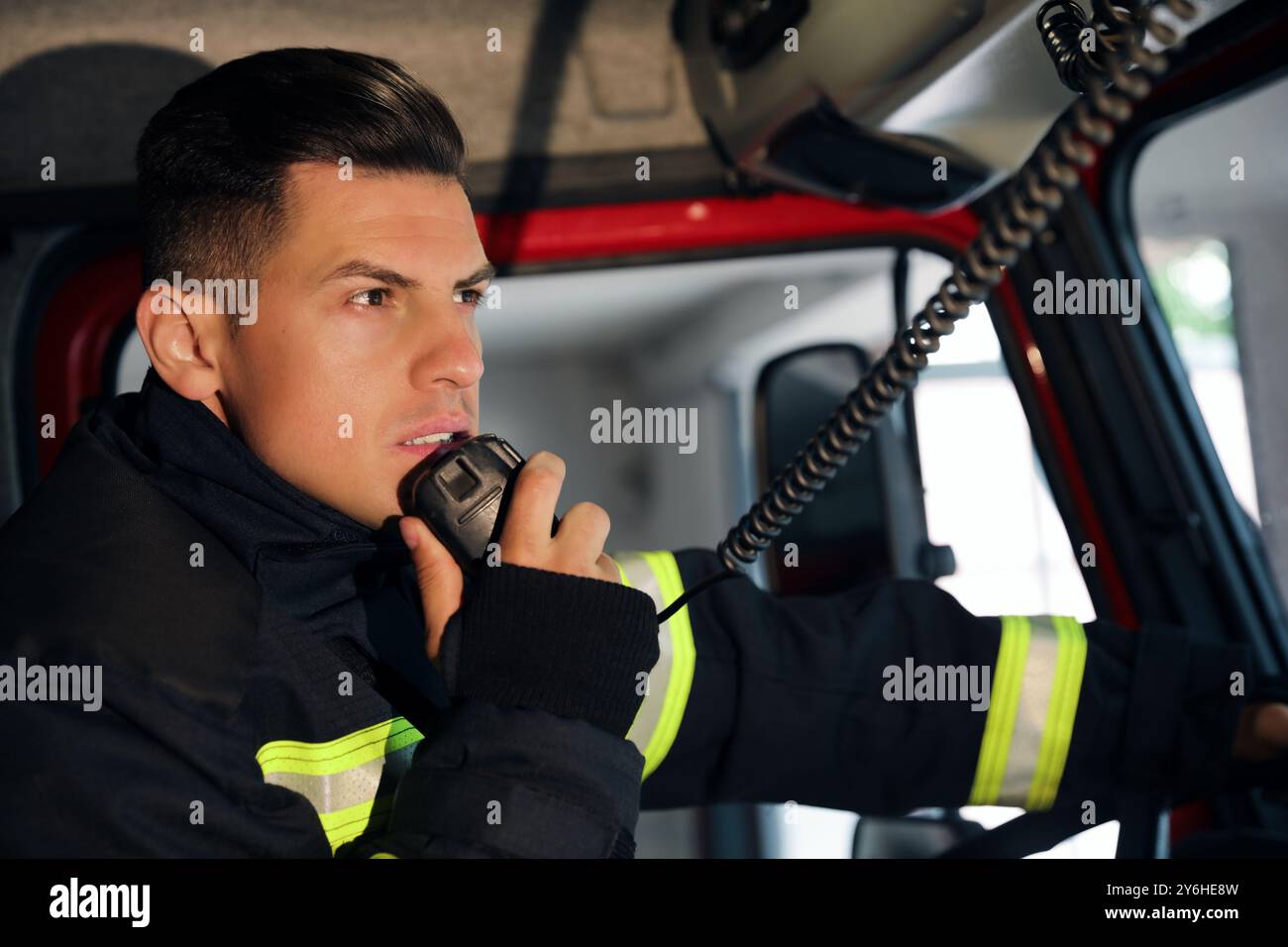 Firefighter using radio set while driving fire truck Stock Photo - Alamy