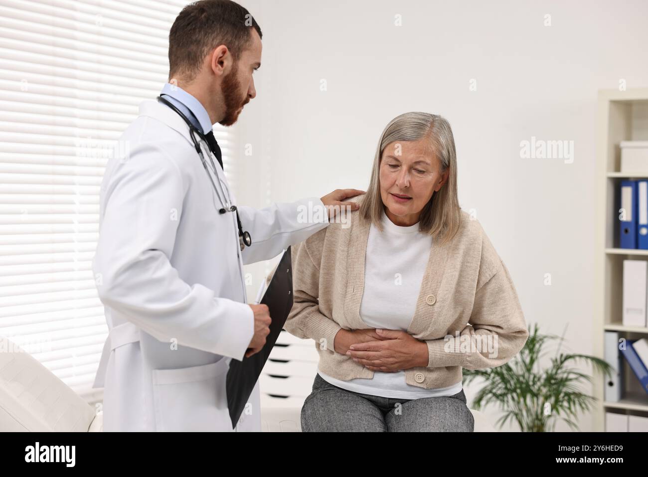 Doctor consulting senior patient with stomach pain in clinic Stock ...
