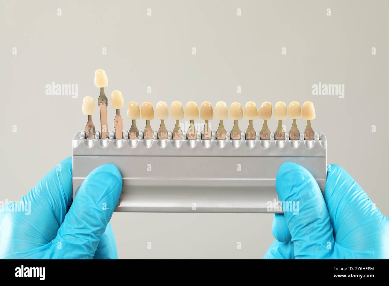 Doctor with teeth color chart on gray background, closeup. Dental ...