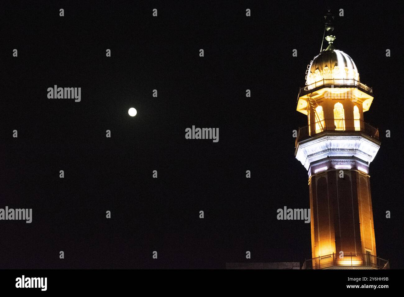 Minaret is shining under the light of the full moon in the dark night ...