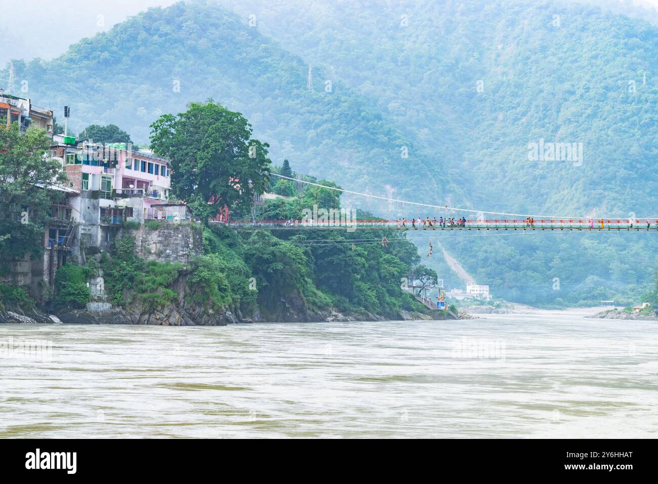 Tourists crossing a suspension bridge over the ganges river in ...