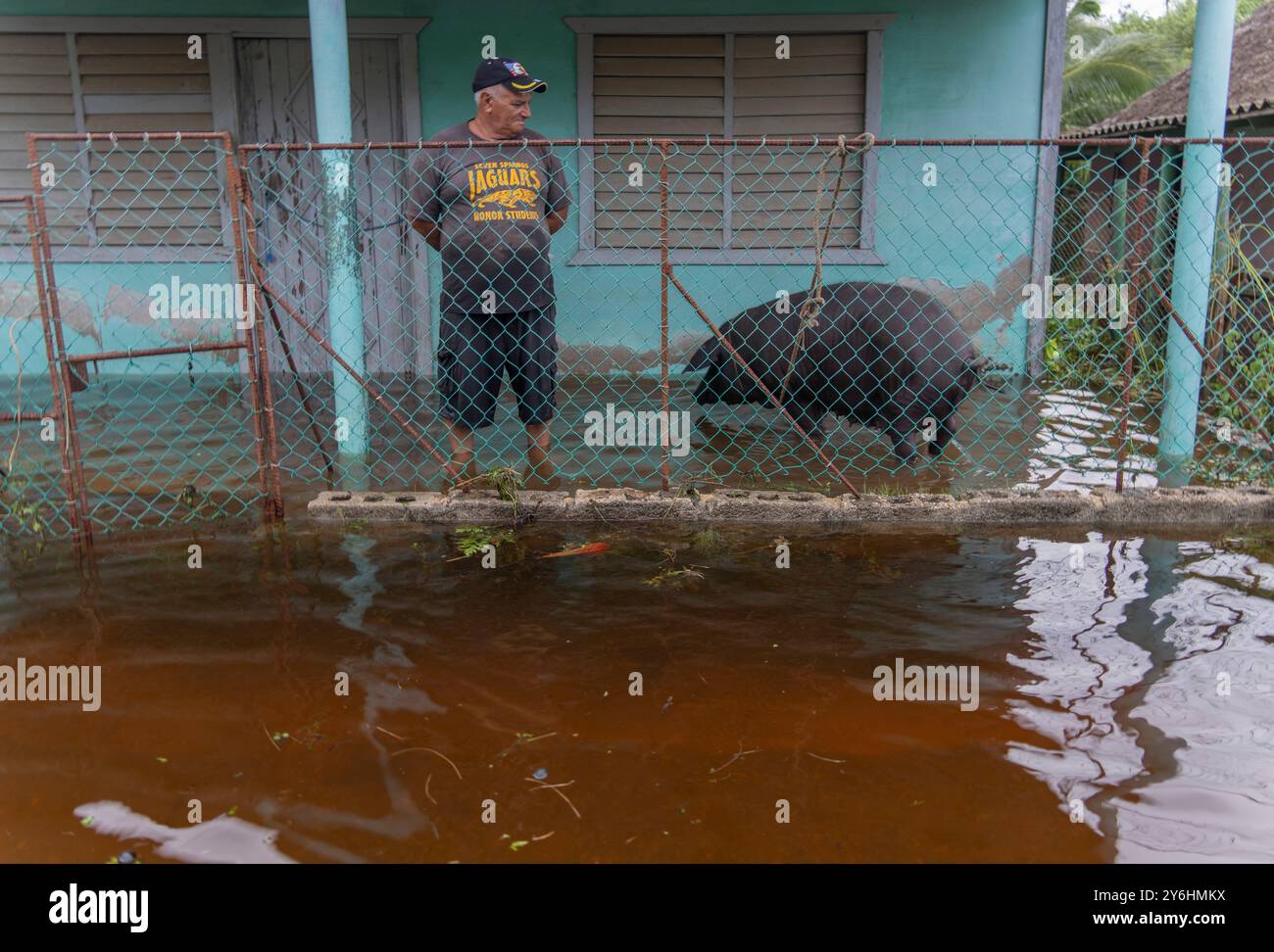 A man spends time with his pig on his flooded porch after the passage ...