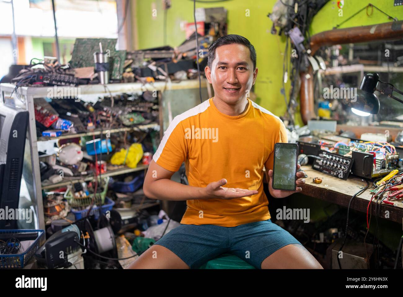 Asian electronics repairman smiles as he shows a cell phone screen ...