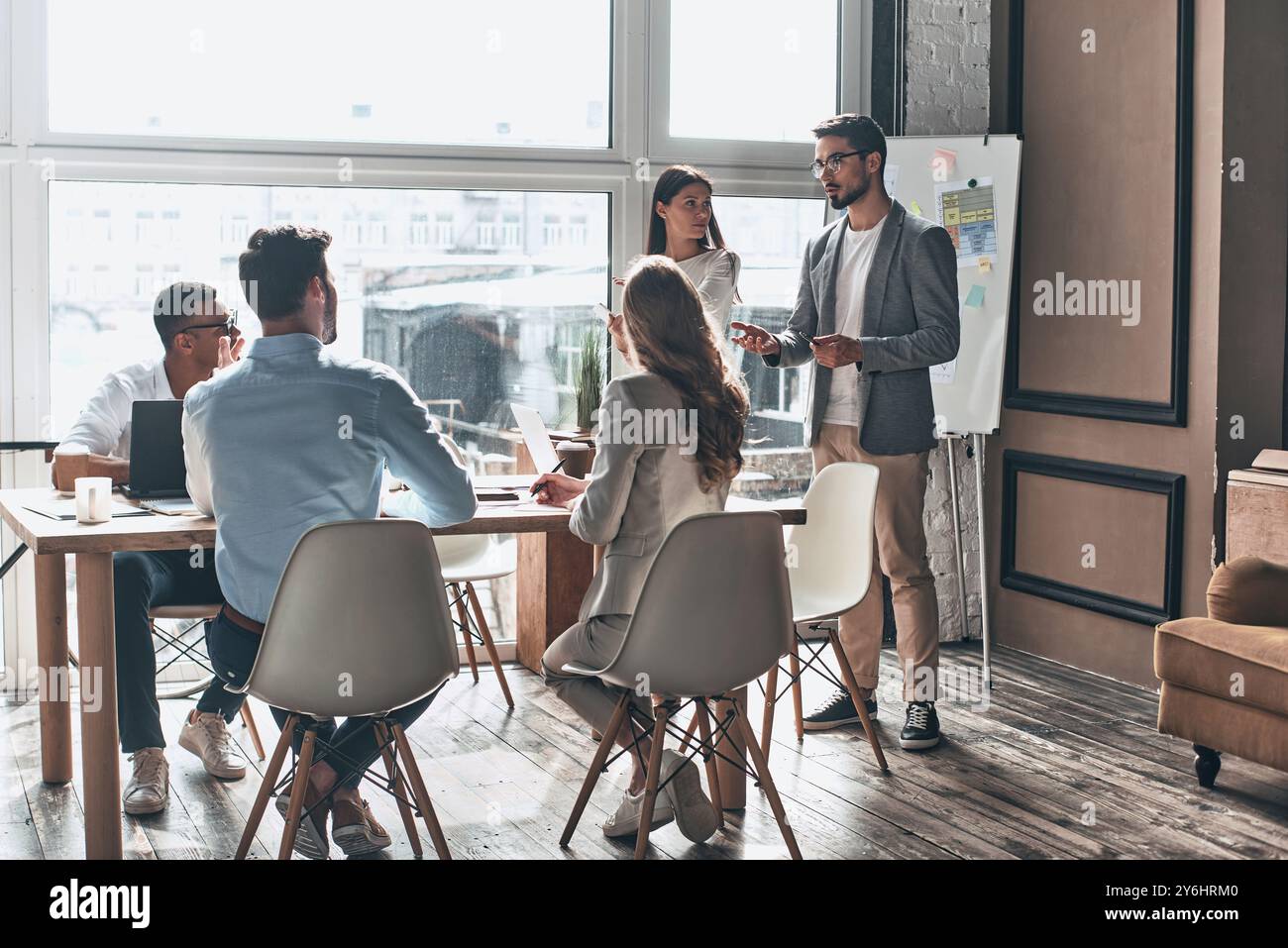 Working as team. Two young colleagues conducting presentation while ...