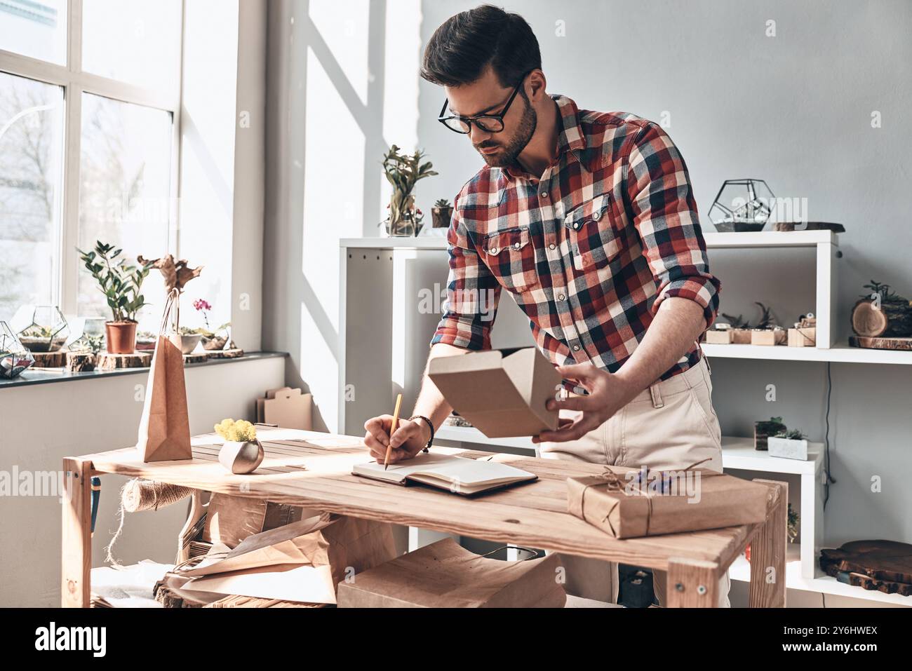 Checking everything. Handsome young man writing something down in his ...