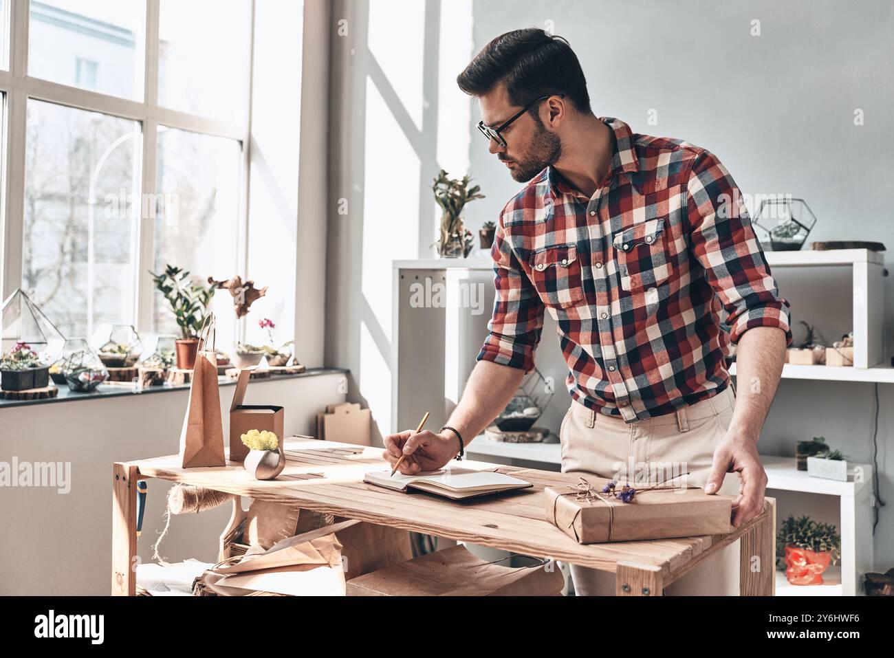 Checking everything carefully. Handsome young man writing something ...