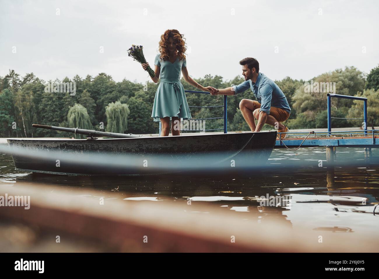Nice day together. Happy young couple getting ready to row a boat while ...