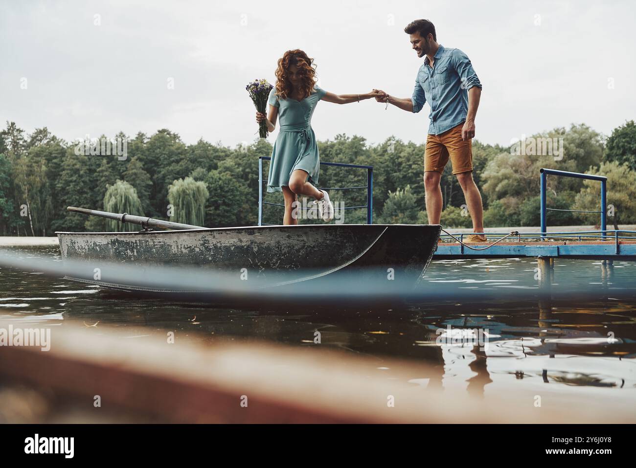 Totally in love. Happy young couple getting ready to row a boat while ...