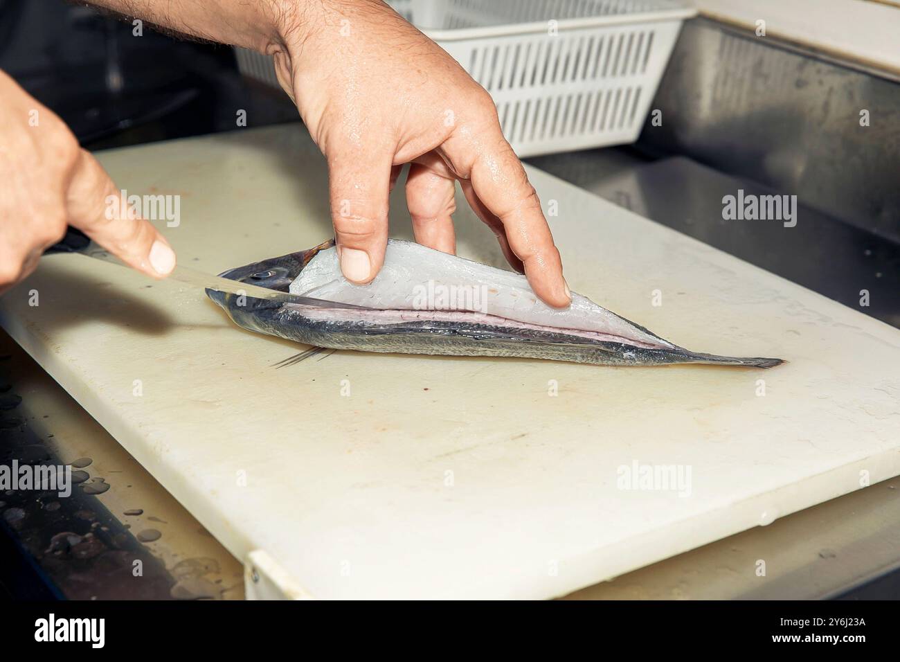 Preparing fresh fish fillet, hands using knife, kitchen cutting board ...