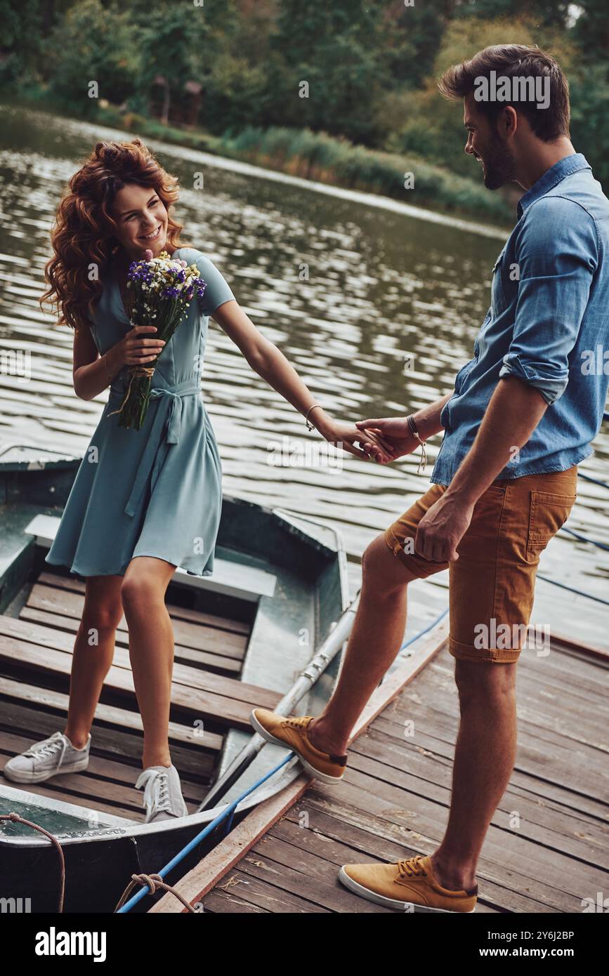 Romantic date. Happy young couple getting ready to row a boat while ...