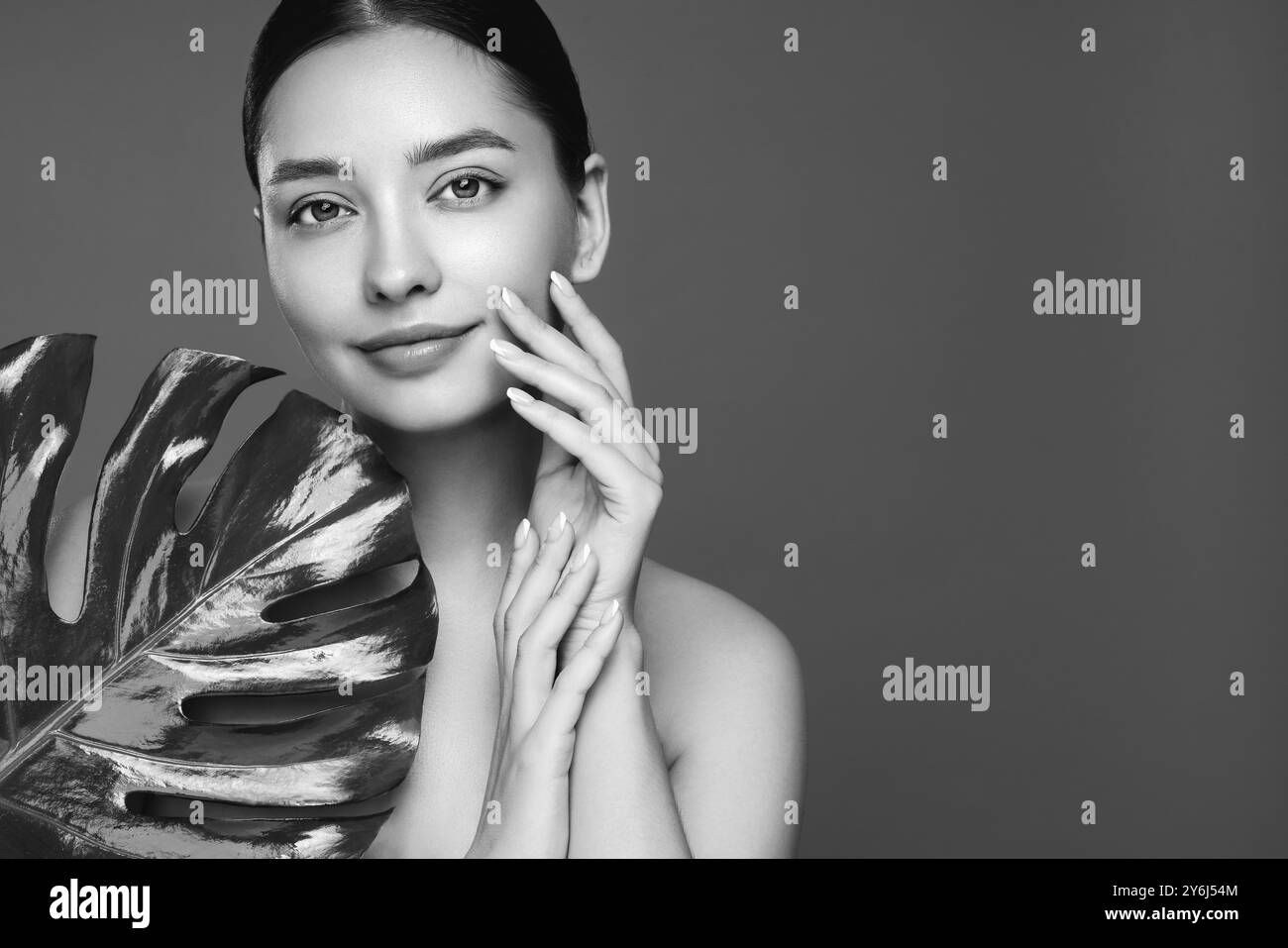 Close up woman face with green exotic leaf. Skin care beauty treatments ...