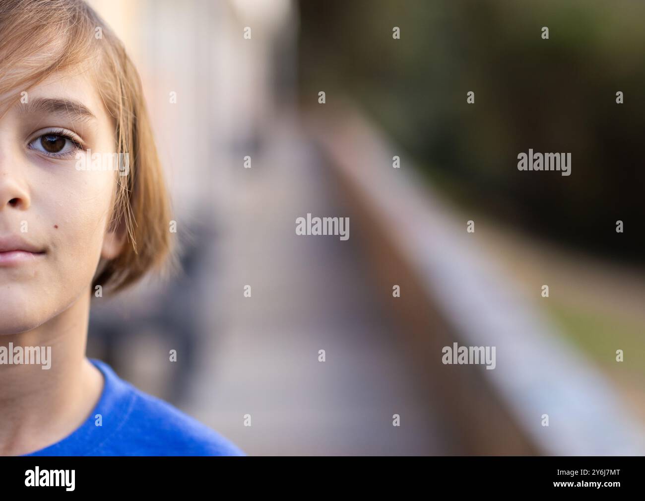 In school, boy standing outside, looking at camera with serious ...