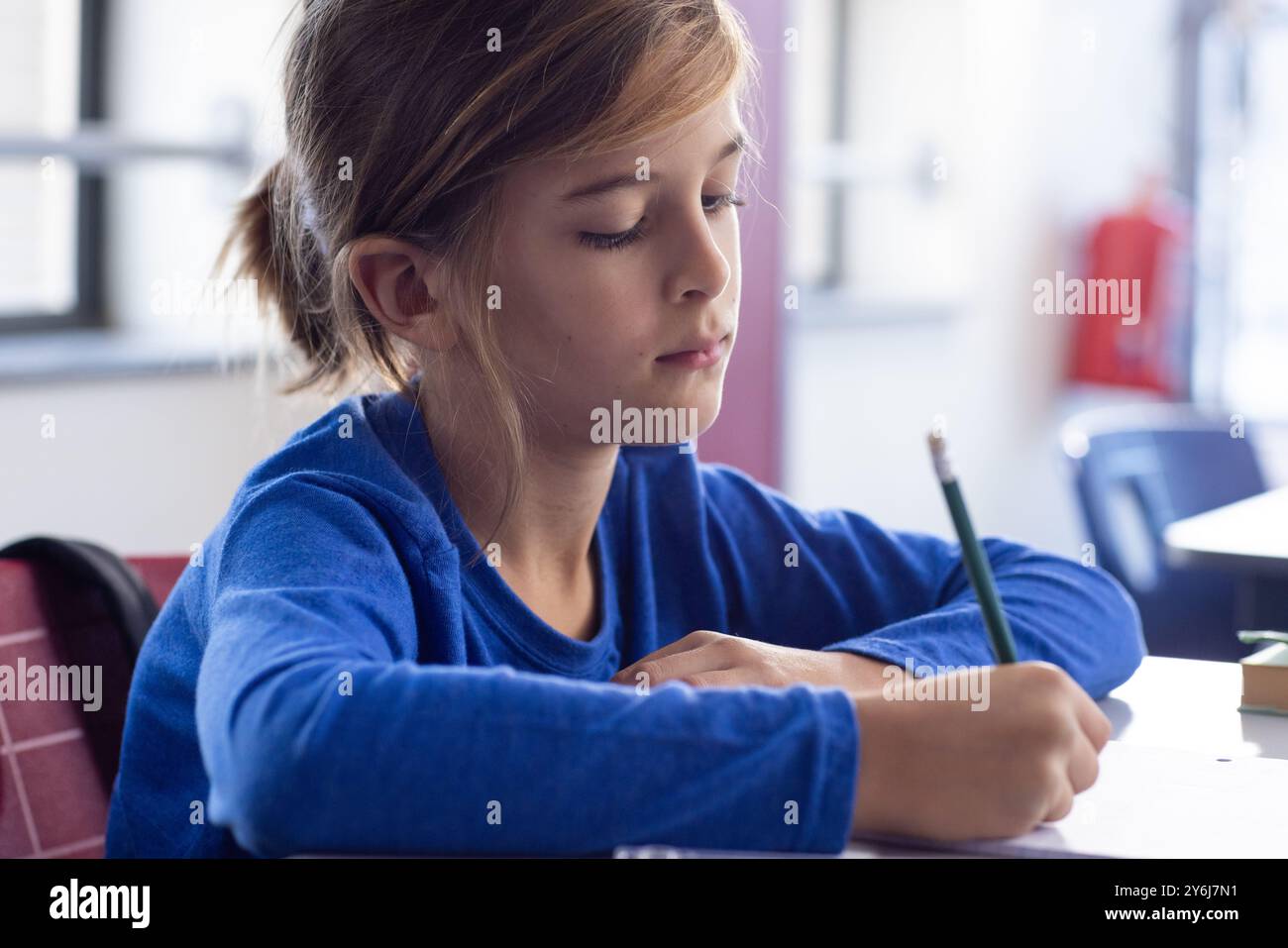 In school, boy writing with pencil in classroom, concentrating on task ...