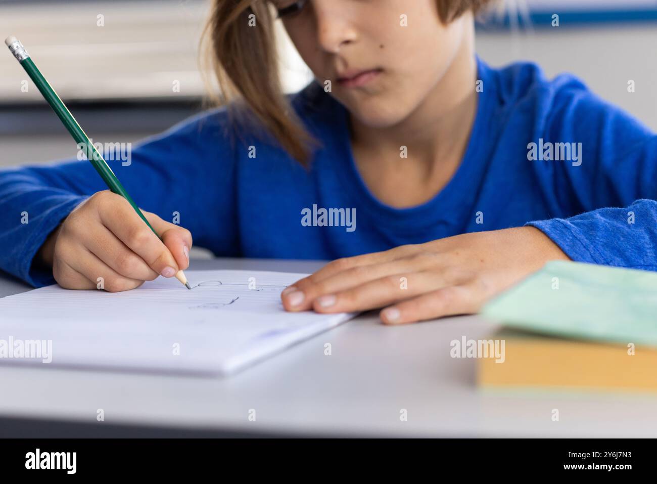 In school, boy writing in notebook, focusing on classroom assignment ...