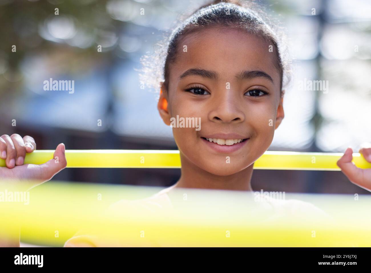Smiling african american girl holding yellow hula hoop, enjoying ...