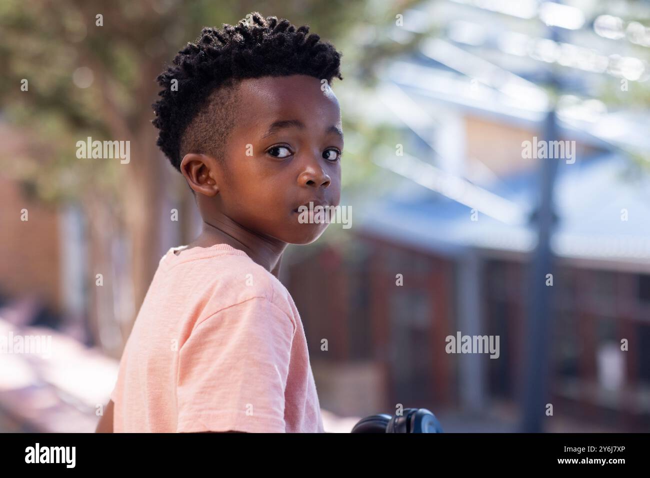 Looking back, young african american boy standing outside school ...