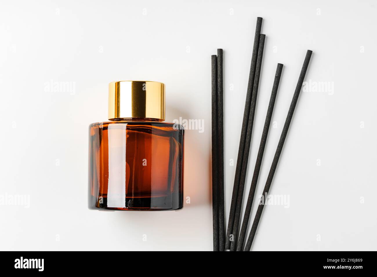 A minimalist display of essential oil and black diffuser sticks on a ...