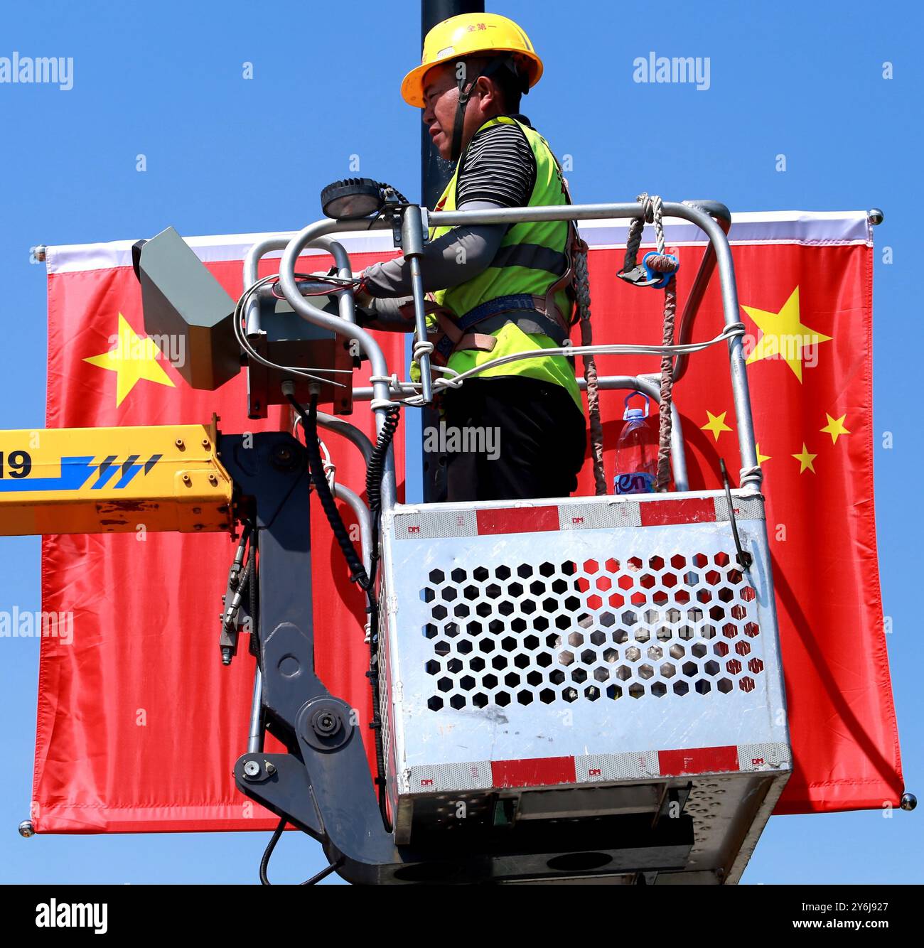 Workers hang the national flags along the street to celebrate the 75th ...