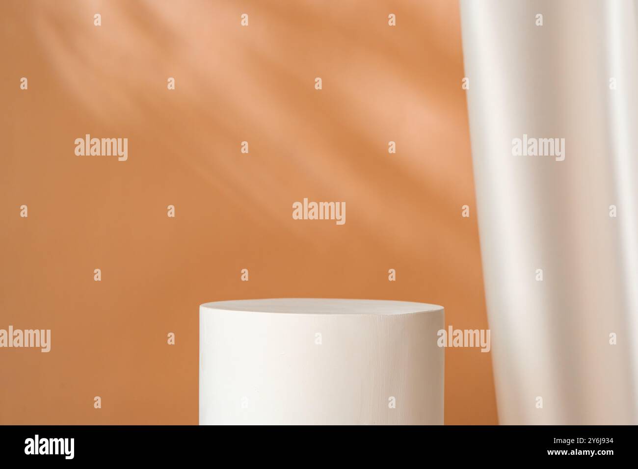 Minimalist decor featuring a white cylinder and draped fabric in a warm ...
