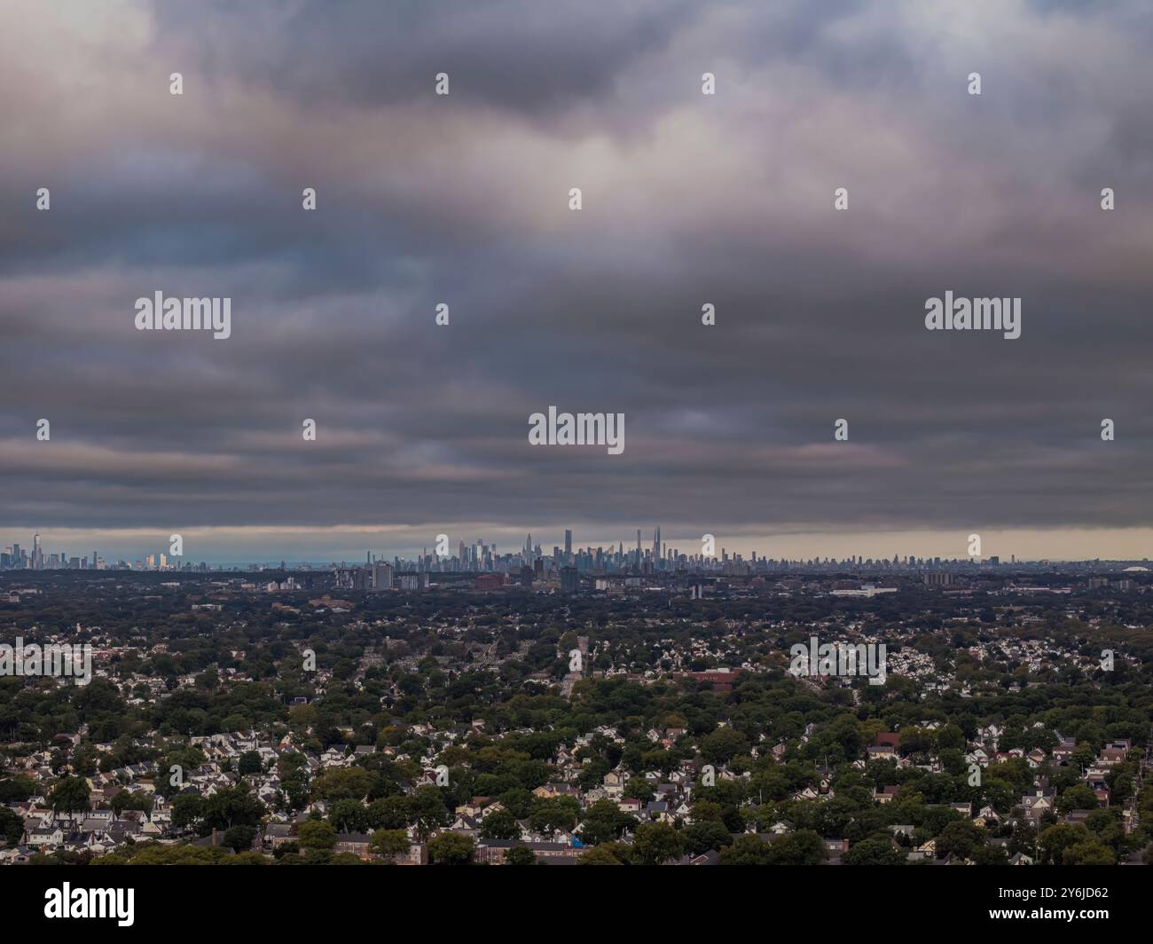 A Panoramic cityscape under dramatic cloudy sky, with hazy skyscrapers ...