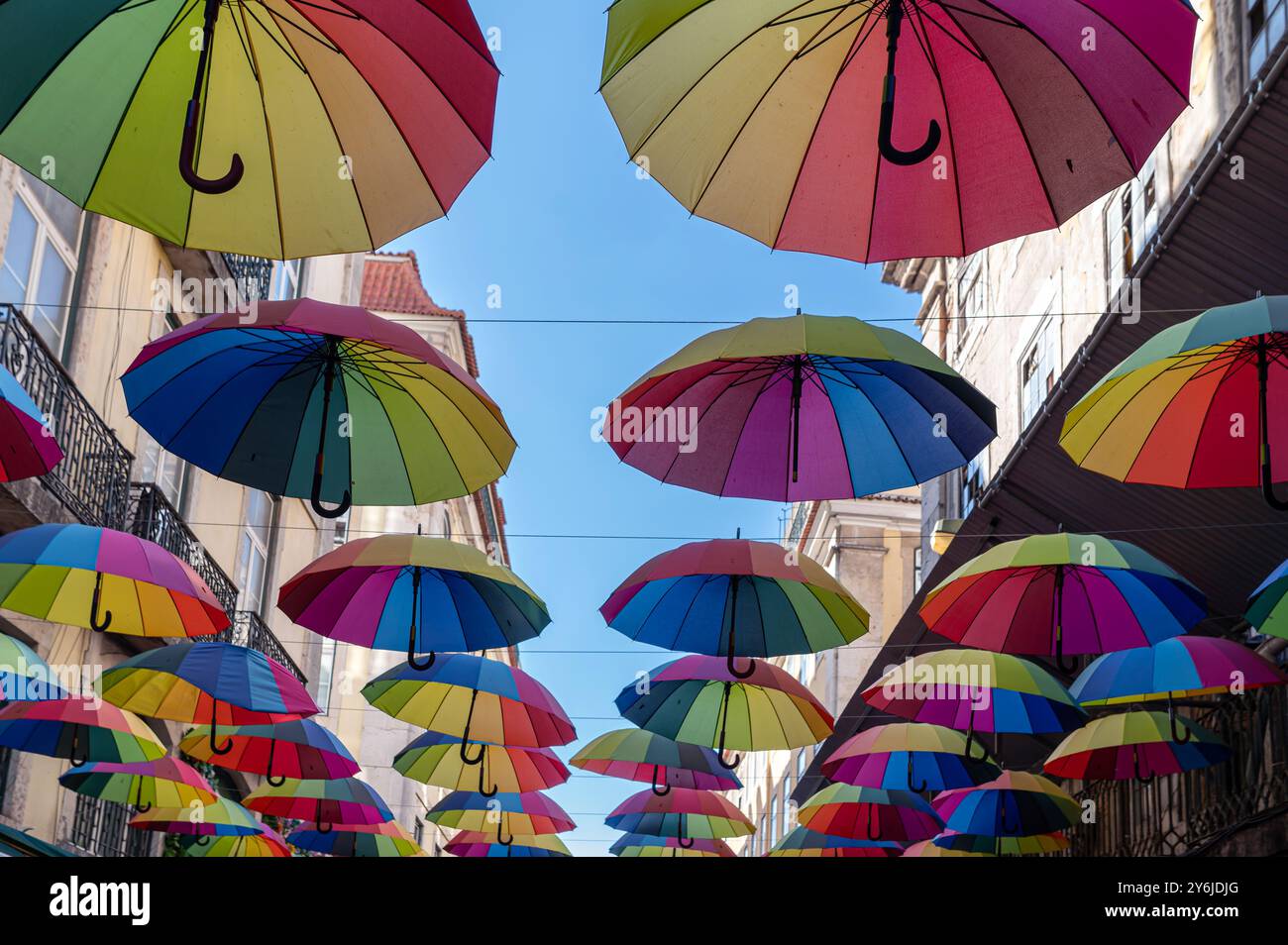 Colorful umbrellas hanging overhead in a vibrant street on a sunny day ...