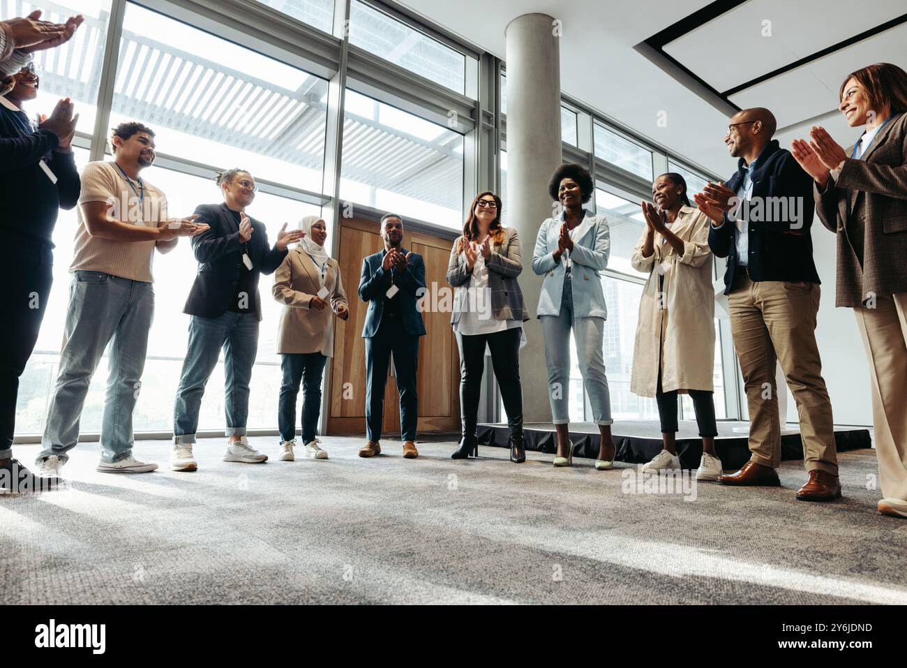 Diverse group of business professionals clapping and celebrating in a ...