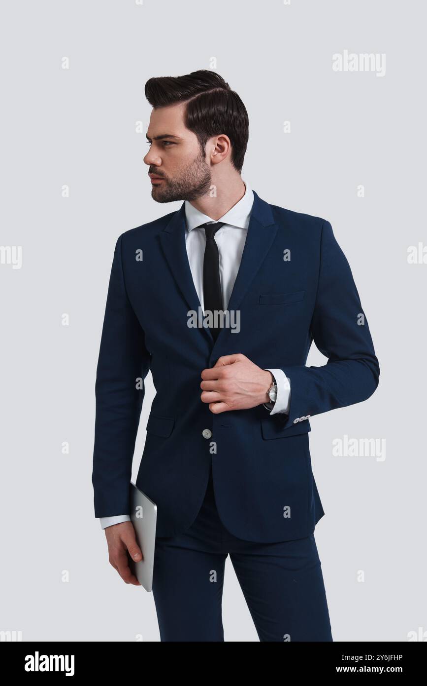 Used to look perfect. Good looking young man in full suit adjusting his ...