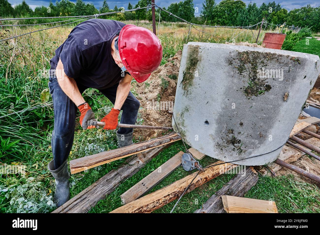 When installing septic tank, builder pushes one concrete ring onto ...