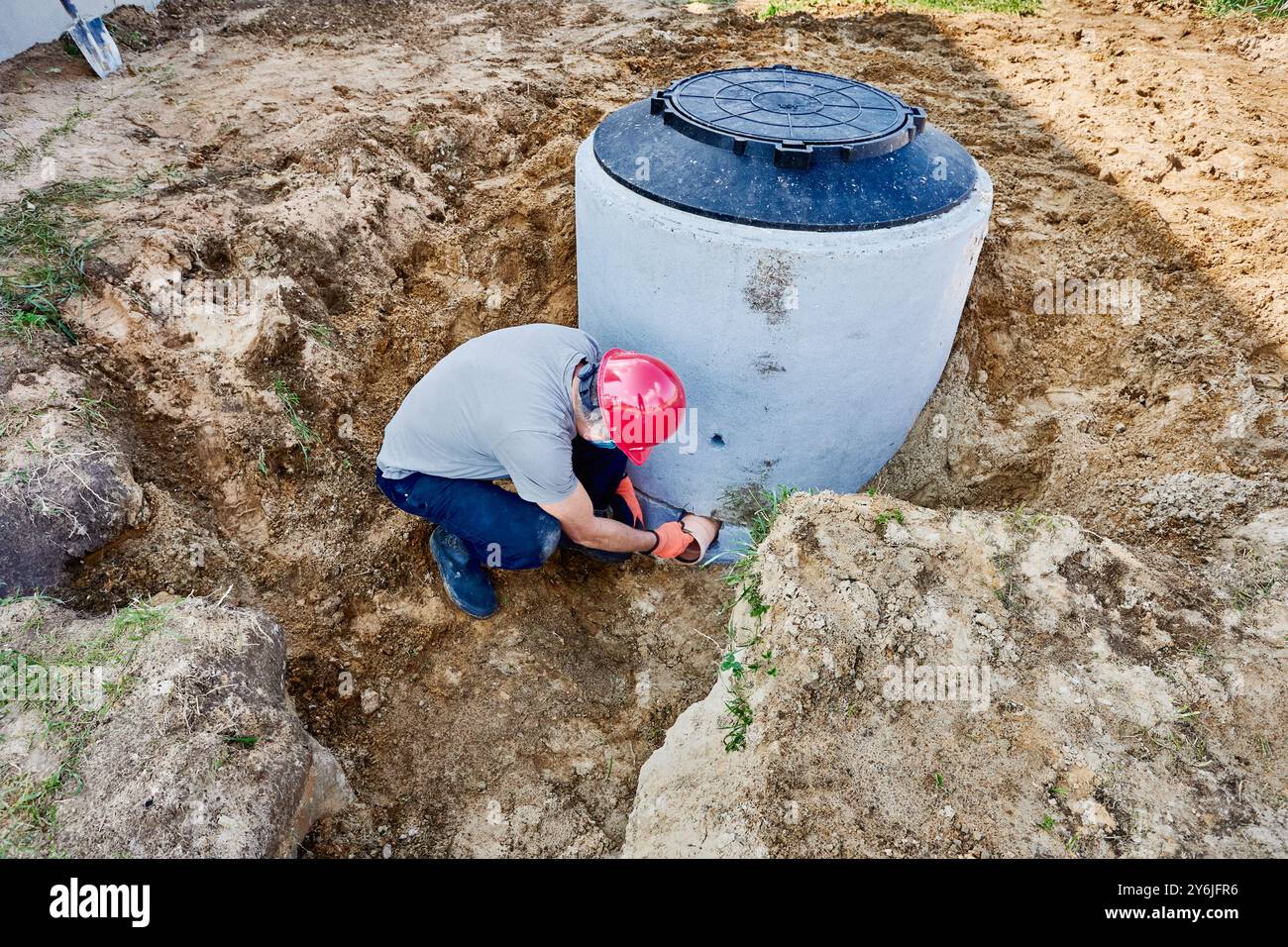 An engineer connects an outlet pipe to concrete septic tank to d Stock ...