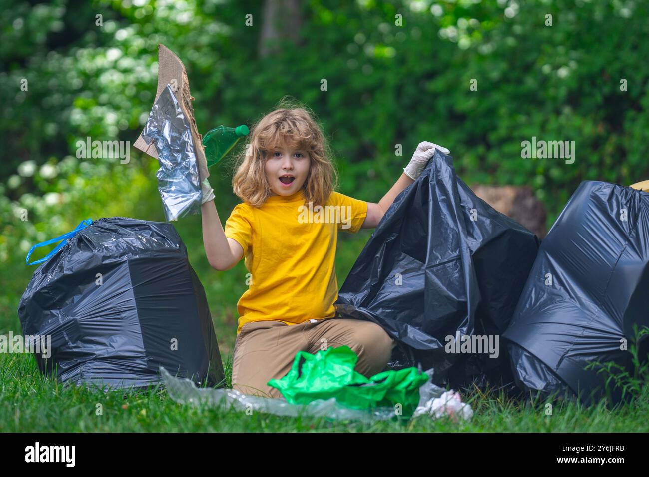 Kid in rubber gloves with trash bag clean up garbage on forest outdoor ...