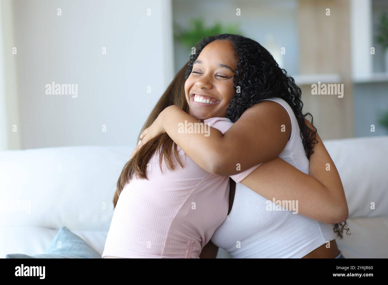 Happy black woman hugging her friend or couple on a sofa at home Stock Photo - Alamy