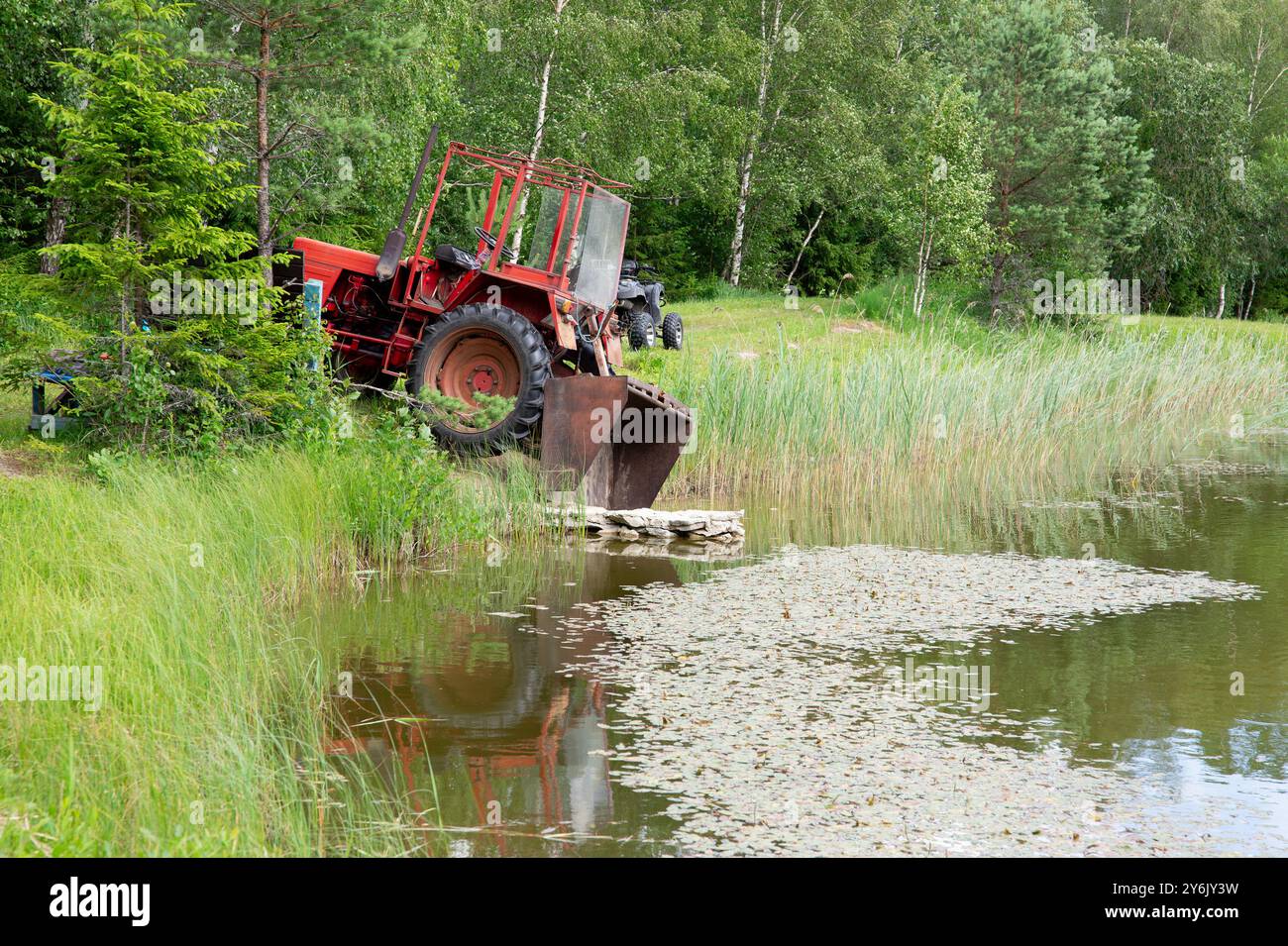 Old tractor in danger of falling and slipping in lake and overturn ...