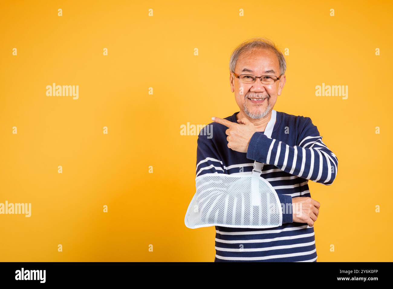 Portrait Asian old man cast on his arm is pointing space studio shot ...