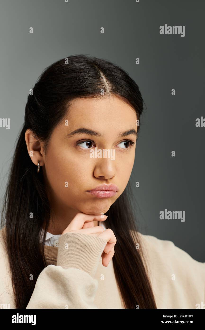 A young woman in fashionable clothing appears lost in thought ...