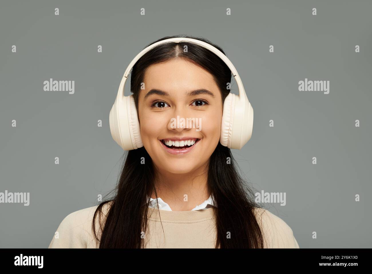 A young woman with headphones smiles brightly, expressing her joy ...