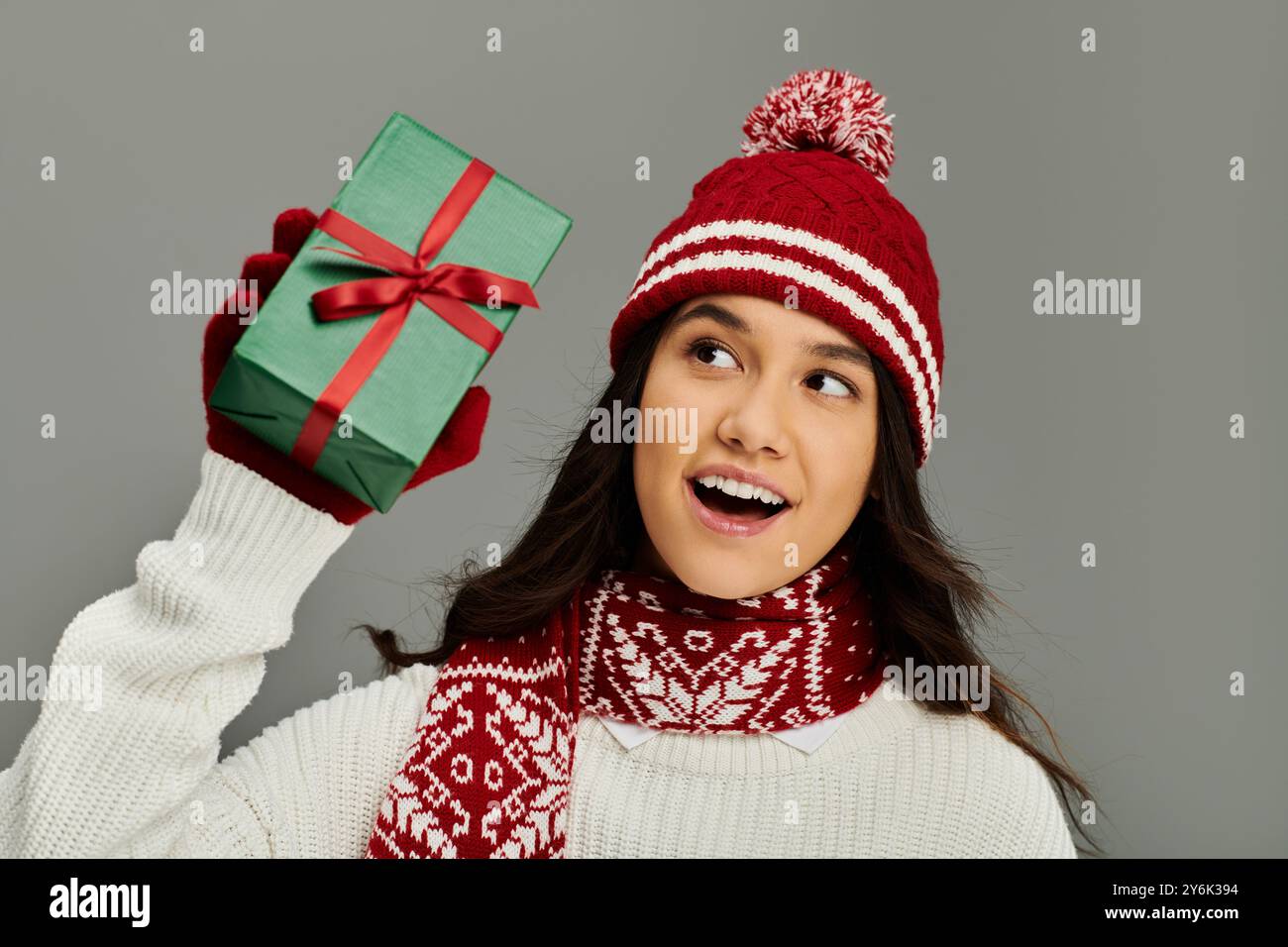A young woman shows her excitement while holding a beautifully wrapped ...