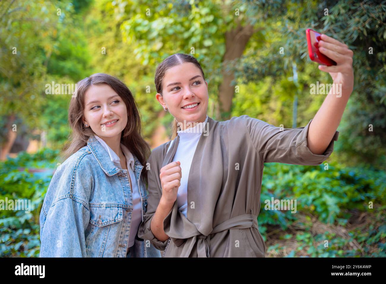 Happy female friends taking a self portrait with cell phone and smiling ...