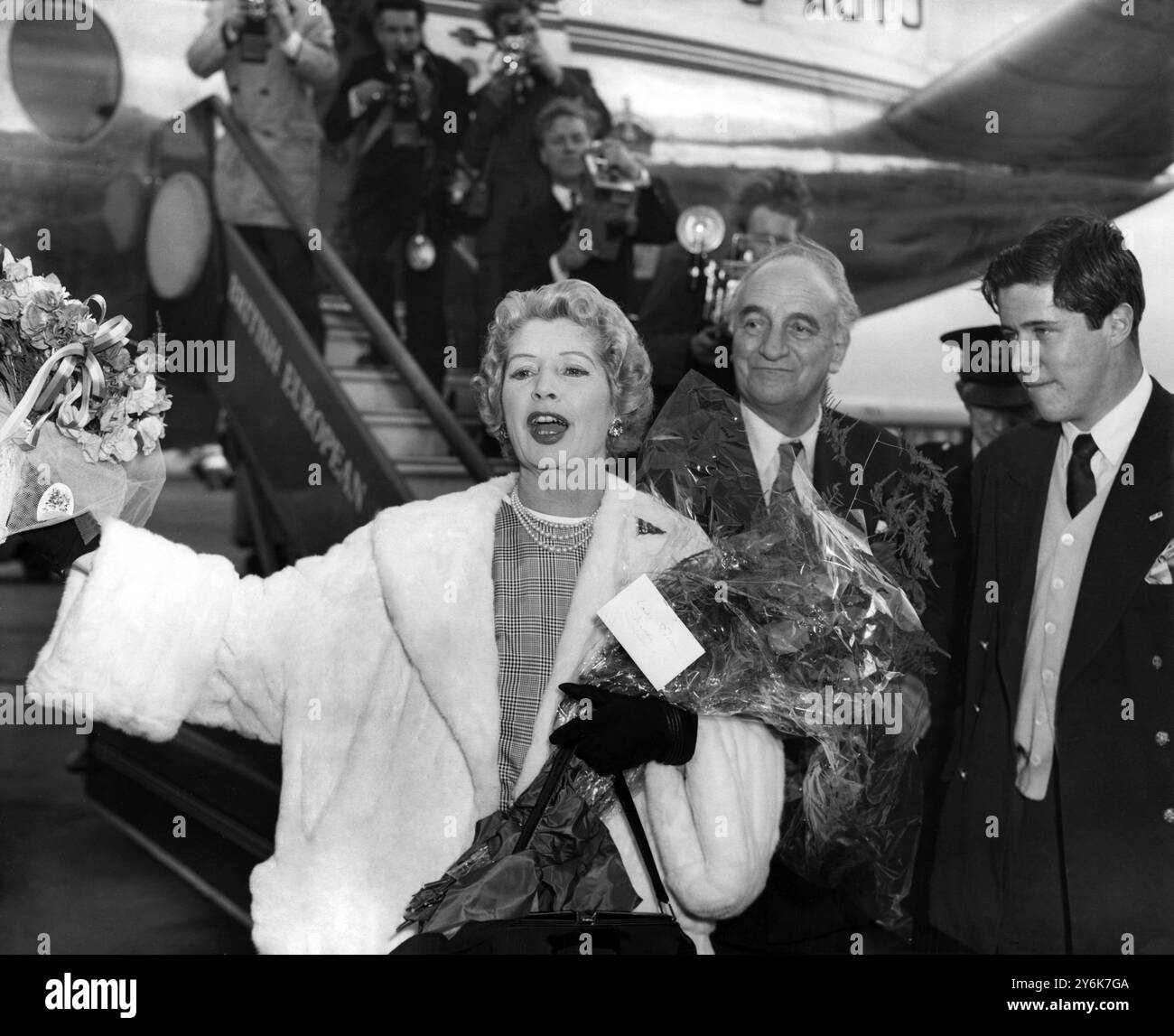 Lady Docker carries a bouquet as she arrives at London Airport with Sir ...